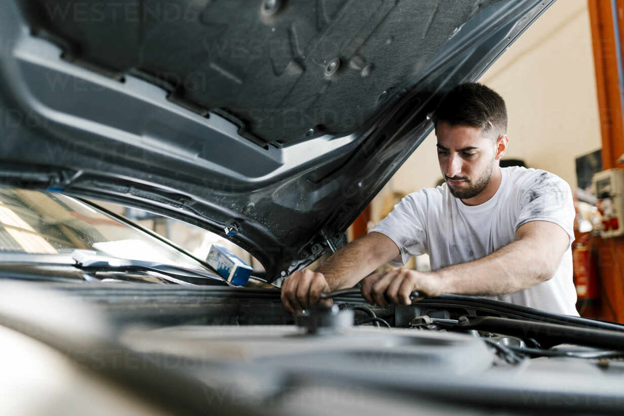 Young man repairing car while standing in auto repair shop stock photo - Worksheets Library